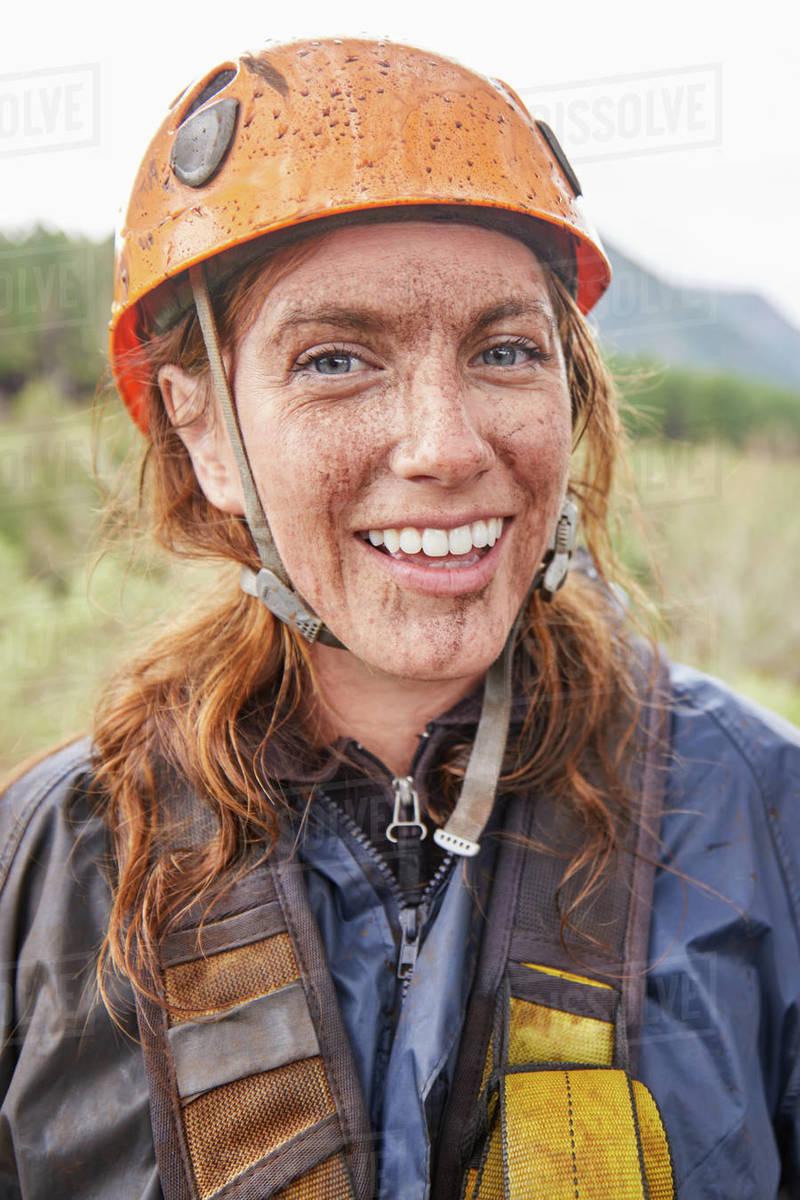 Portrait smiling, muddy woman zip lining - Stock Photo - Dissolve