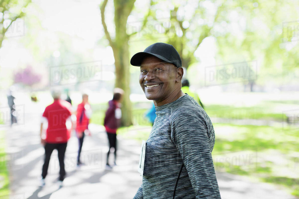 Portrait confident, happy senior man walking sports race in park ...