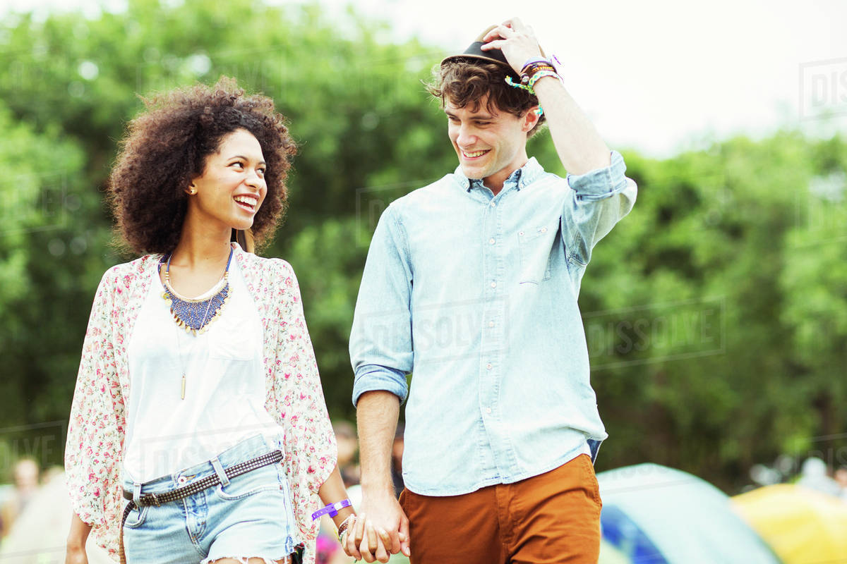 Couple holding hands outside tents at music festival - Royalty-free ...