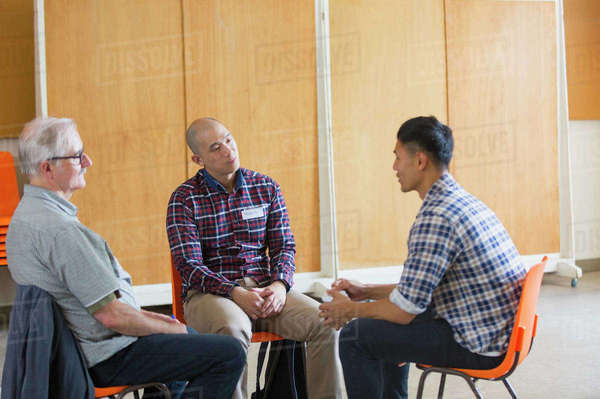 Men talking and listening in group therapy - Stock Photo - Dissolve