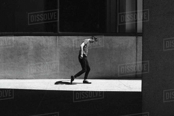 Shadow following man walking on sunny pavement - Stock Photo - Dissolve