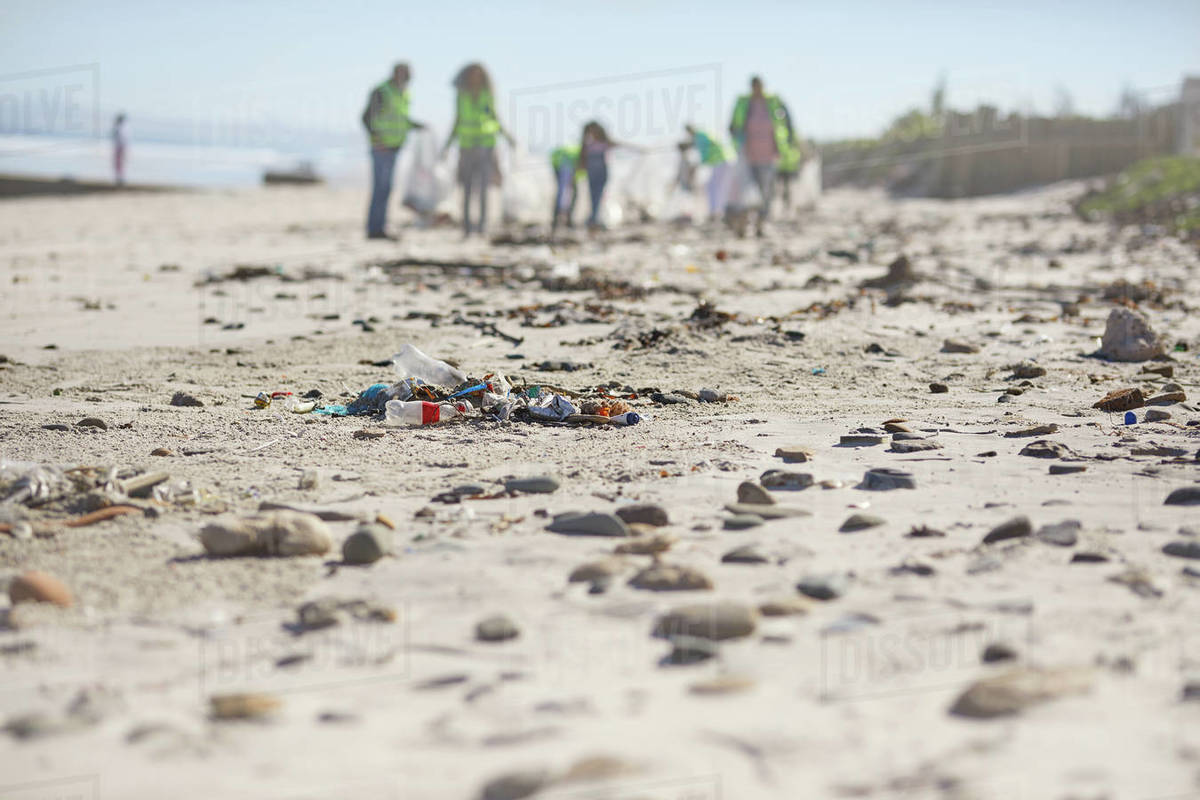 Volunteers cleaning up litter on sunny, sandy beach - Royalty-free ...