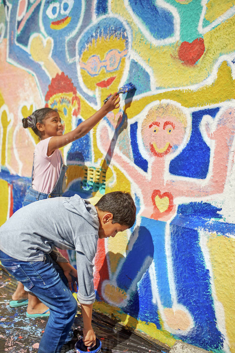 Children painting vibrant mural on sunny wall - Royalty-free Stock ...