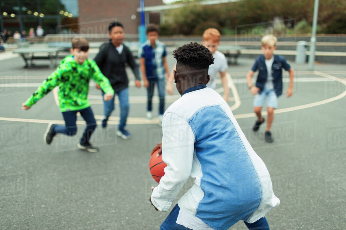 Tween boys playing basketball in schoolyard - Stock Photo - Dissolve