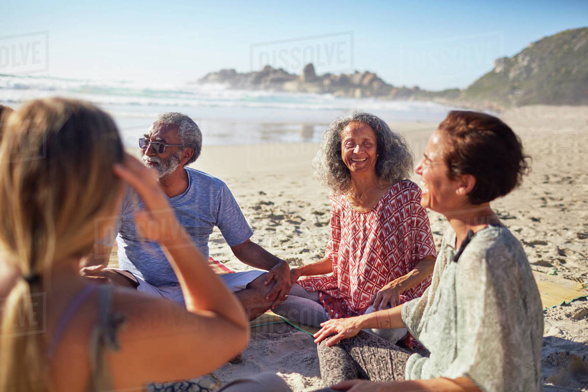 Friends sitting in circle on sunny beach during yoga retreat - Royalty ...