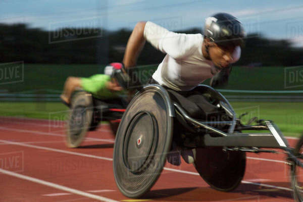 Determined young male paraplegic athlete speeding along sports track in ...