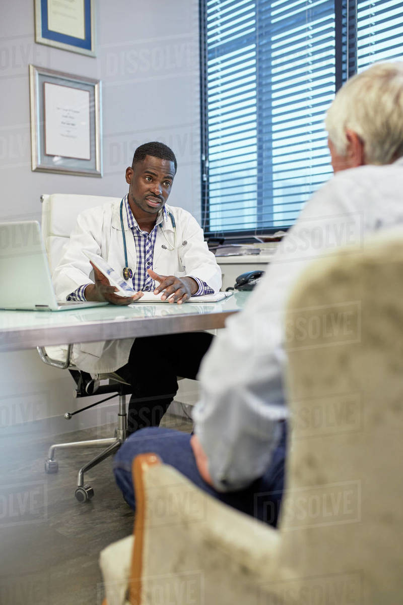 Doctor with digital tablet talking to patient in doctors office ...