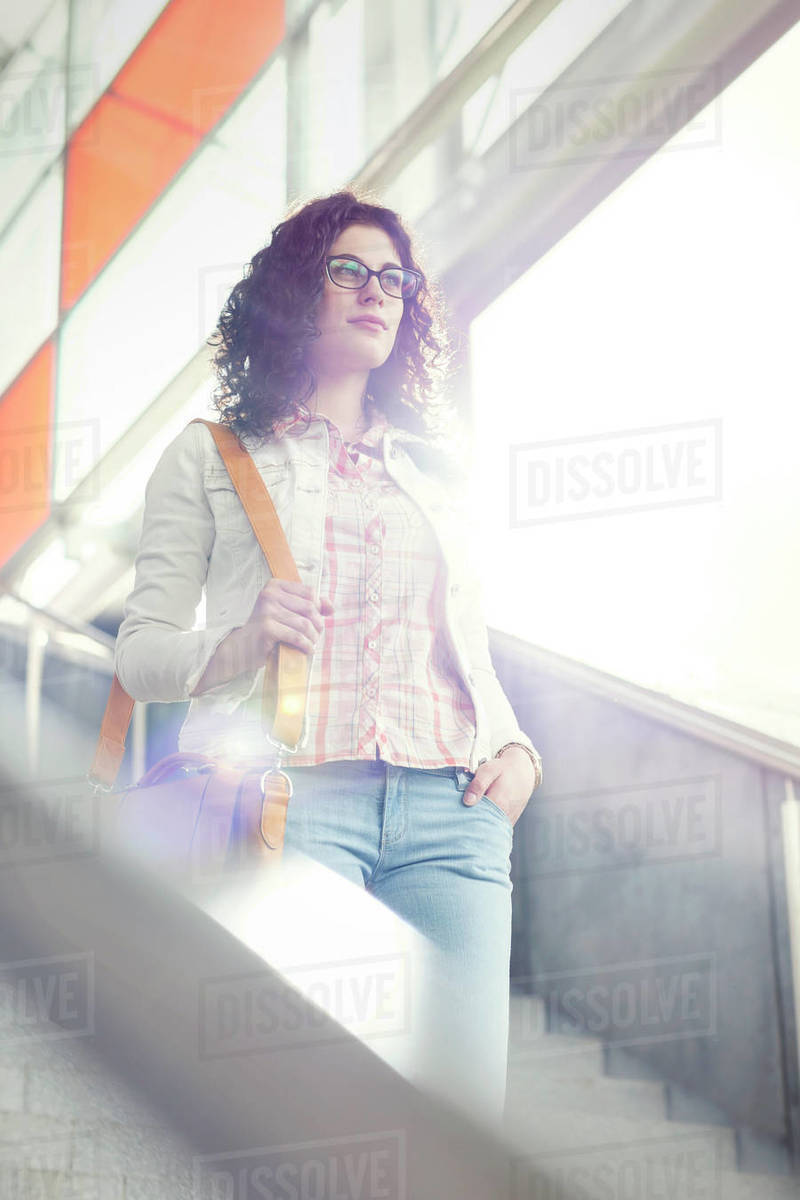 Confident young woman descending stairs - Royalty-free Stock Photo | Dissolve