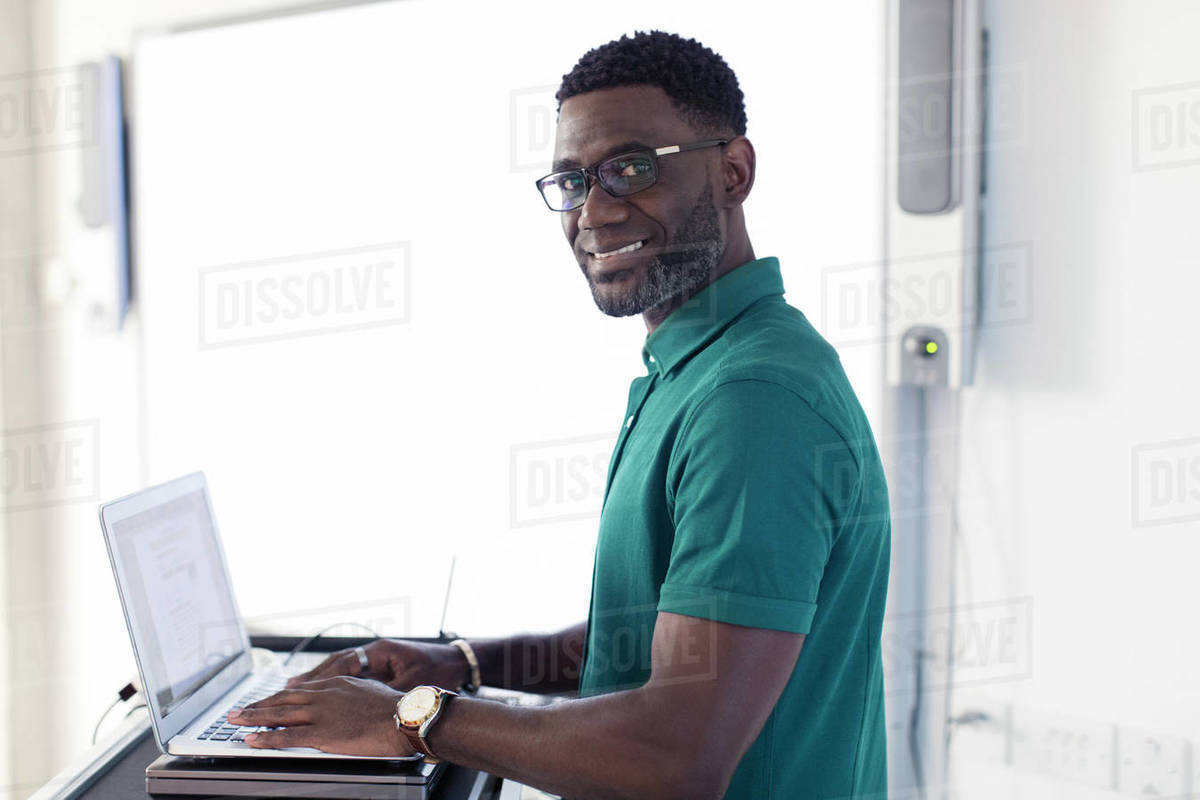 Portrait smiling, confident male instructor at laptop preparing in ...