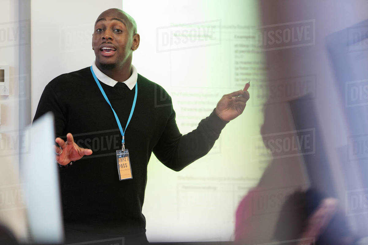 Male instructor leading lesson at projection screen in classroom ...