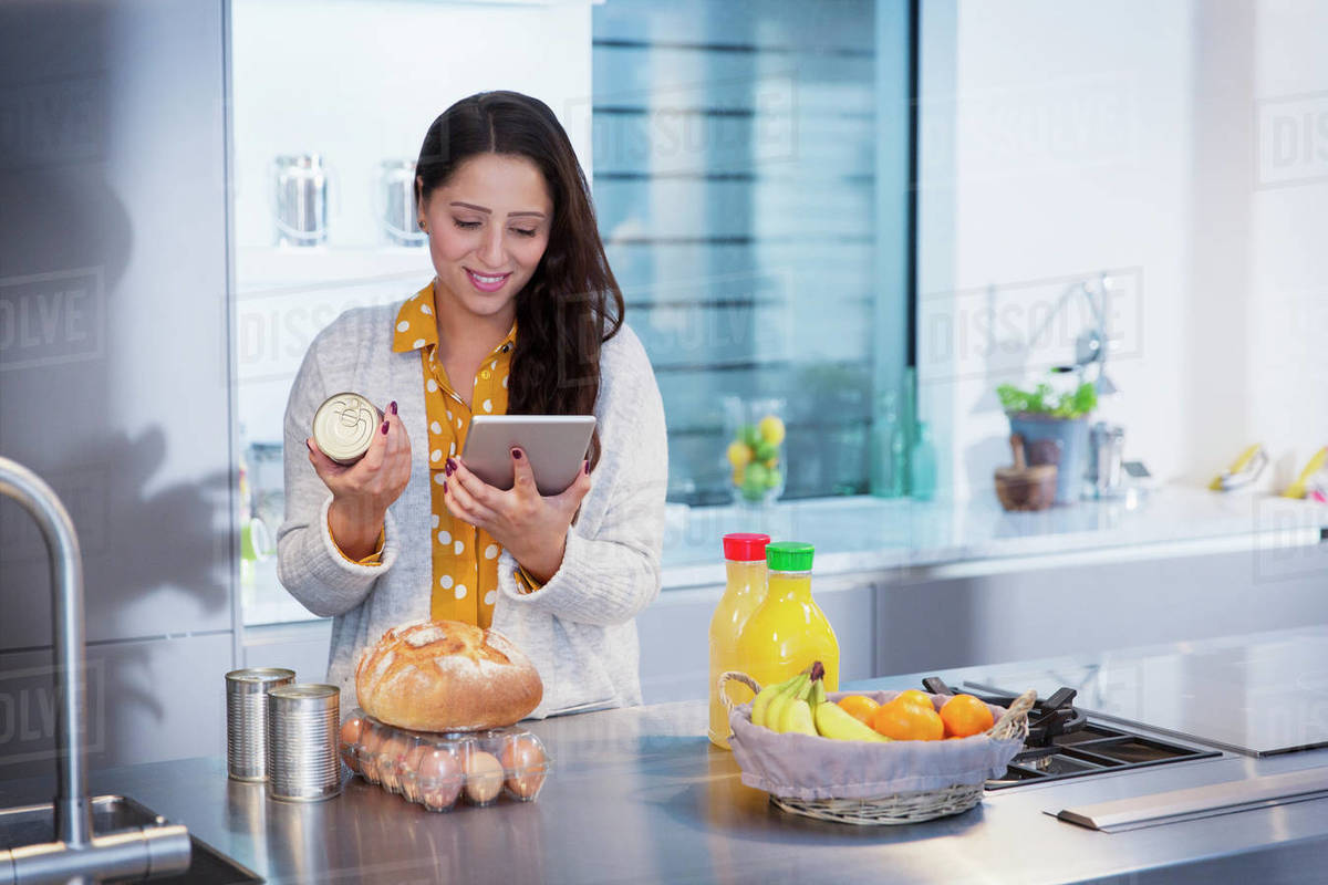 Woman with digital tablet checking food labels in kitchen - Royalty ...