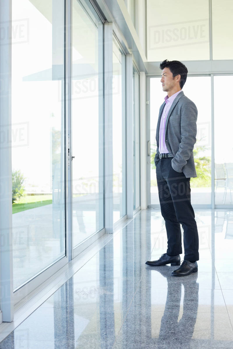 Businessman standing at office window - Stock Photo - Dissolve