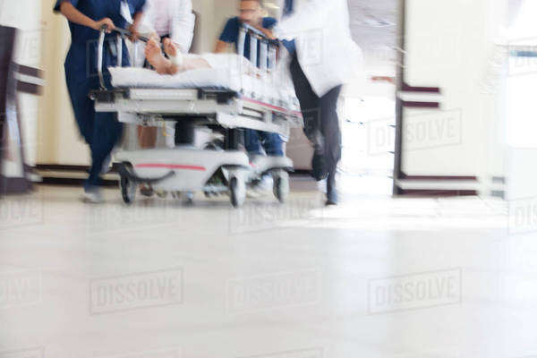 Hospital staff rushing patient to operating room - Stock Photo - Dissolve