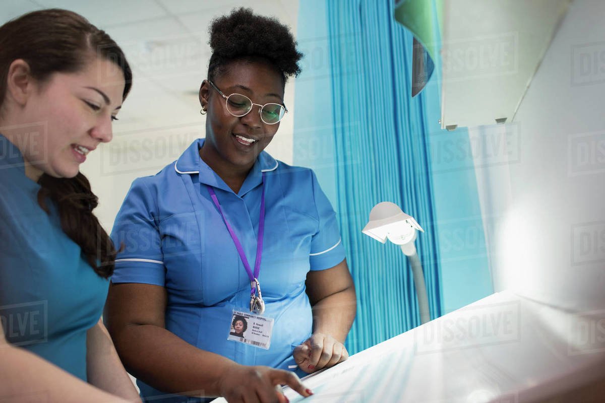 Female nurses discussing paperwork in hospital room - Royalty-free ...