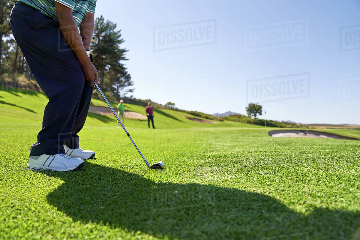 Male golfer taking a shot on sunny golf course - Stock Photo - Dissolve