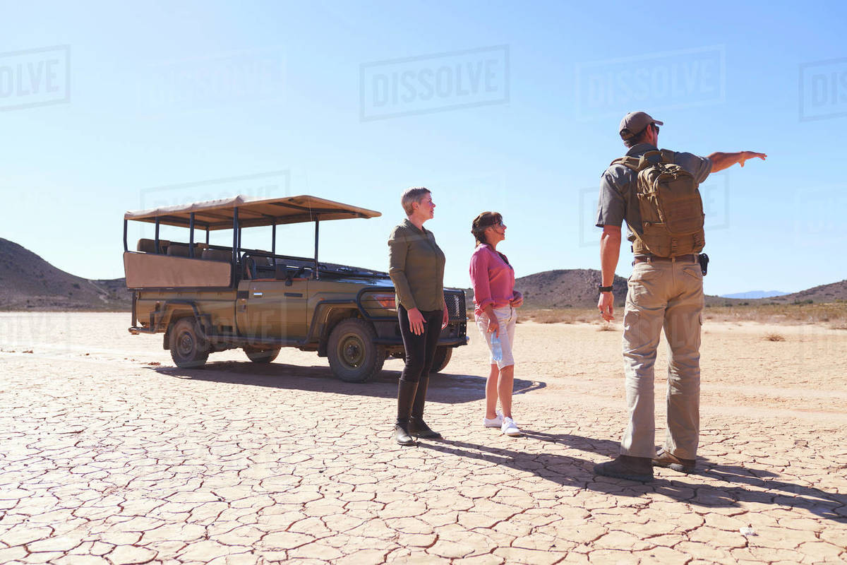 Safari tour guide talking tourists in sunny arid desert South Africa ...