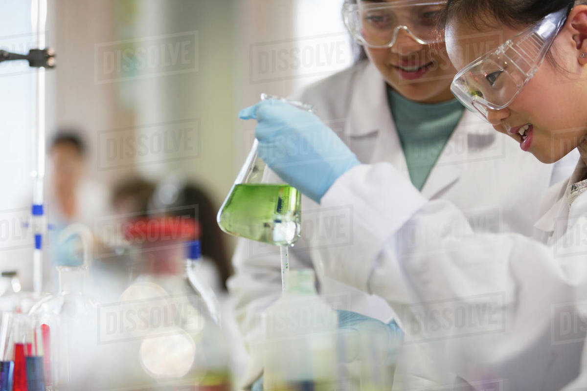 Girl students conducting scientific experiment, examining liquid in ...