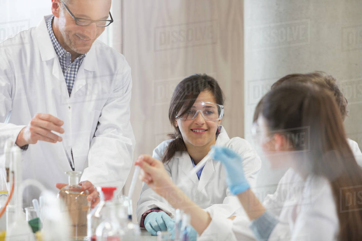 Male teacher and students conducting scientific experiment in ...