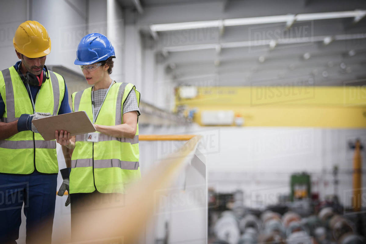 Supervisors with clipboard talking on platform in factory - Royalty ...