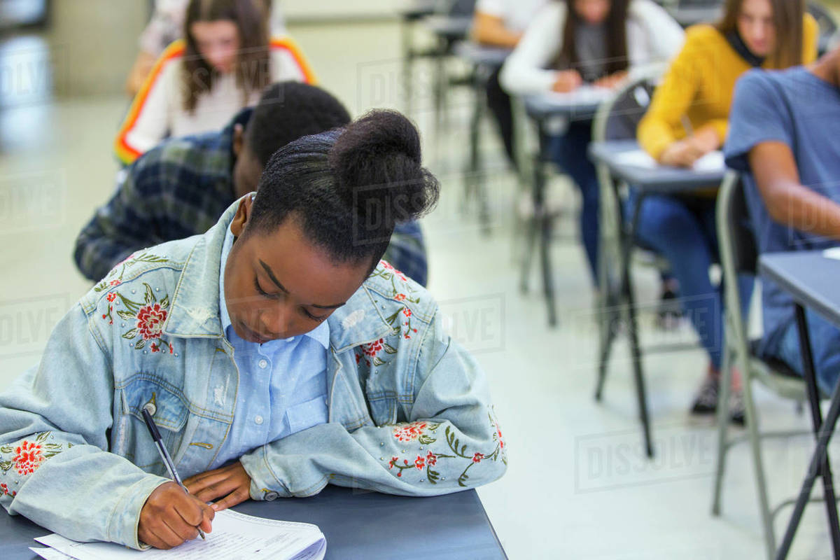 Focused high school girl student taking exam at desk in classroom ...