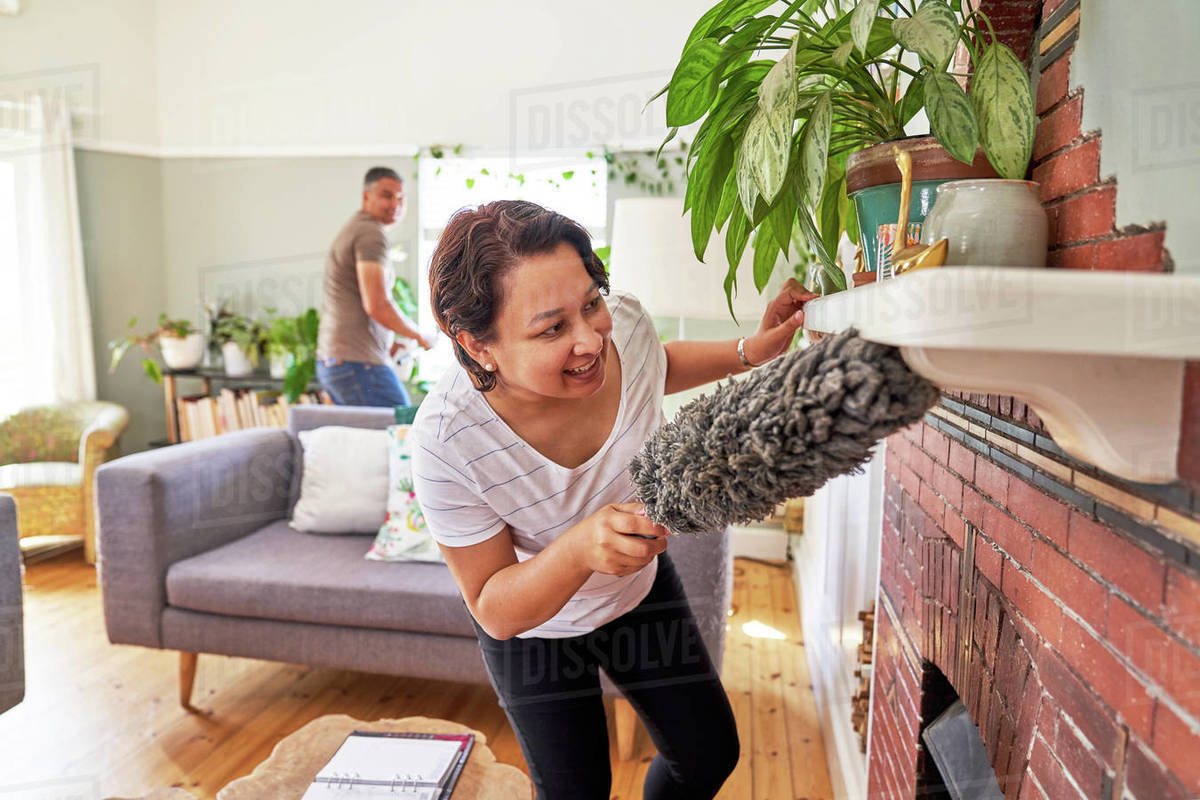 Mature woman with duster dusting fireplace mantel - Stock Photo - Dissolve