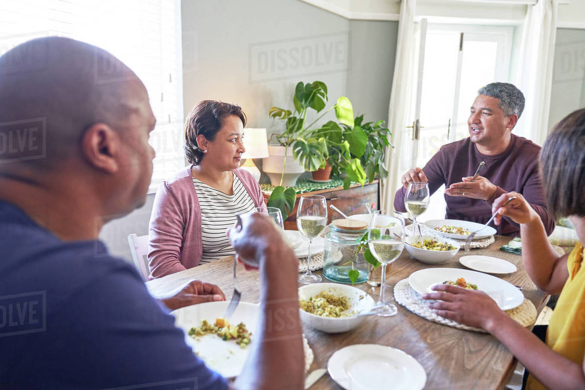 Mature couple friends talking and eating lunch at dining table ...