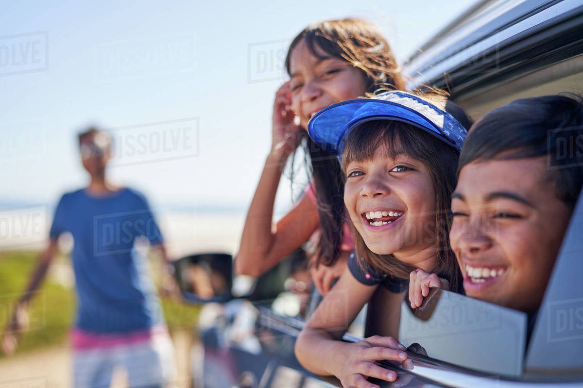 Portrait happy kids leaning out sunny car window - Stock Photo - Dissolve