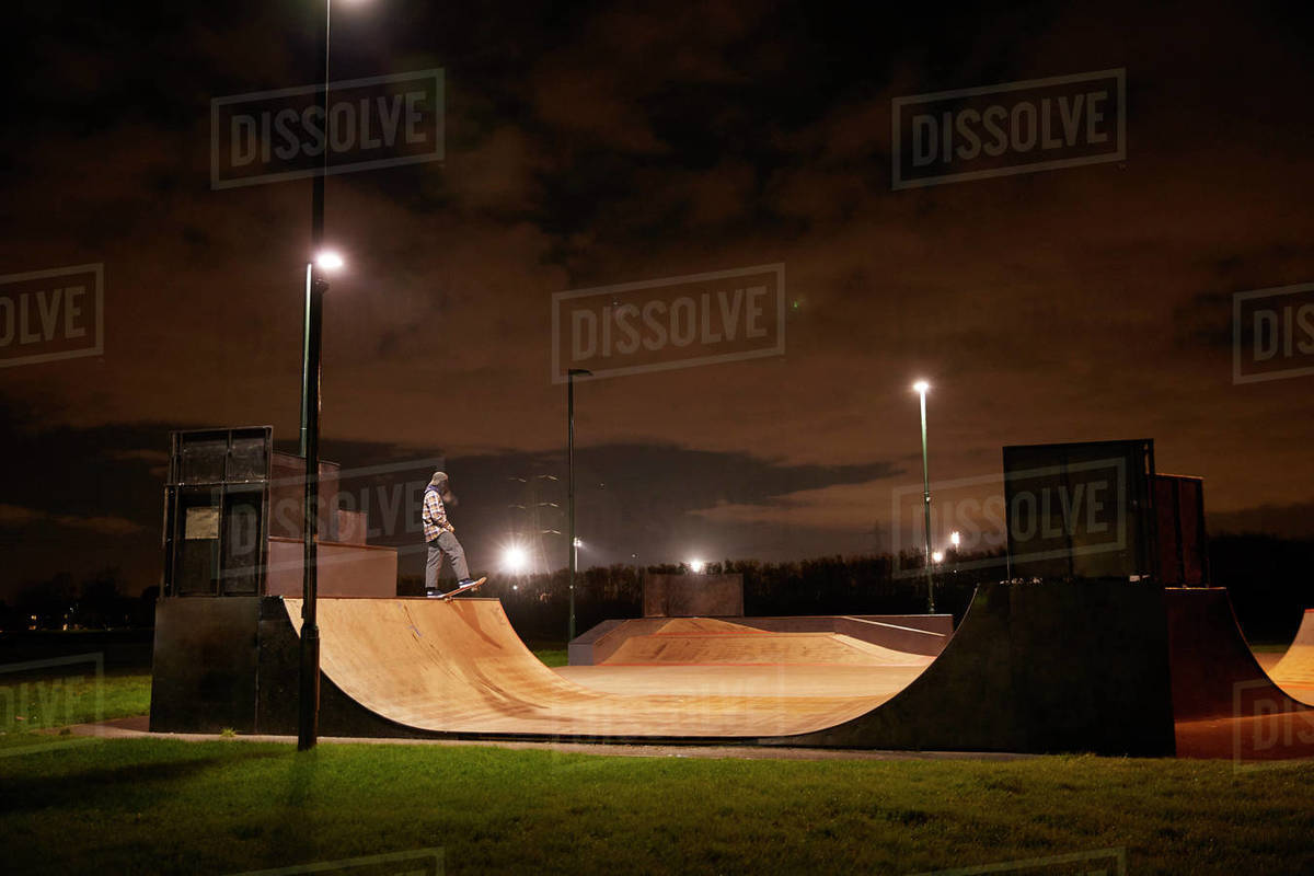 Young man skateboarding on skate park ramp at night - Royalty-free ...