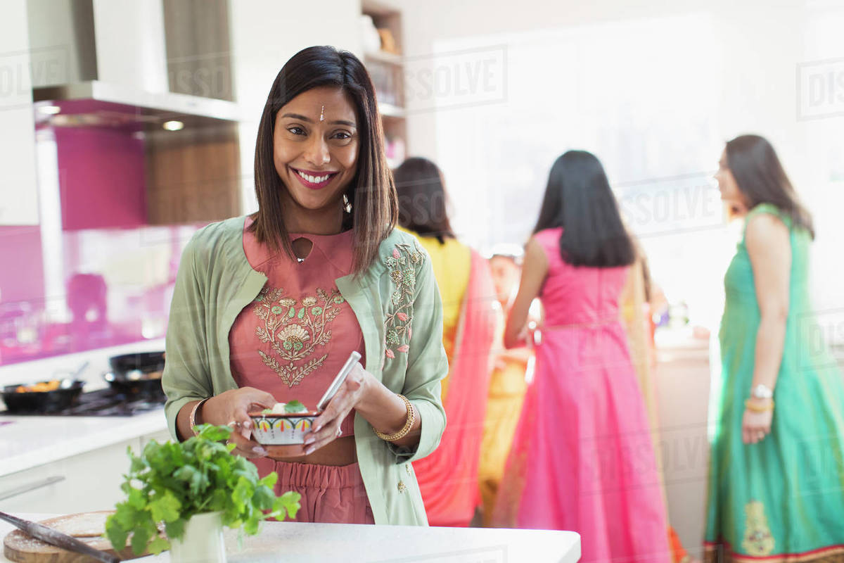 Portrait happy Indian woman in sari and bind cooking food in kitchen ...