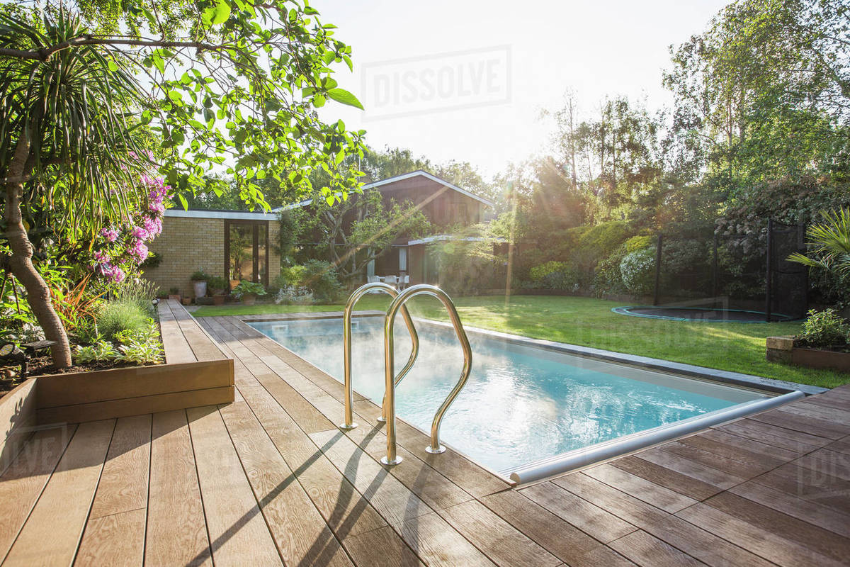 Sunny idyllic home showcase swimming pool and backyard - Stock Photo ...