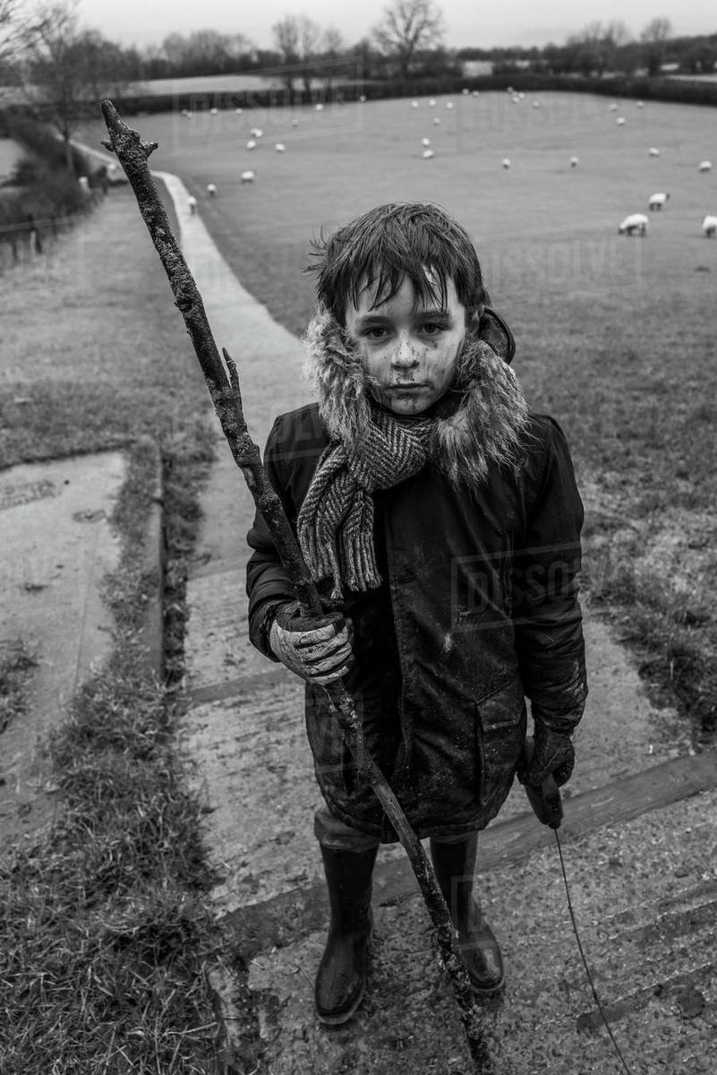 Portrait muddy boy with stick in rural field - Royalty-free Stock Photo ...