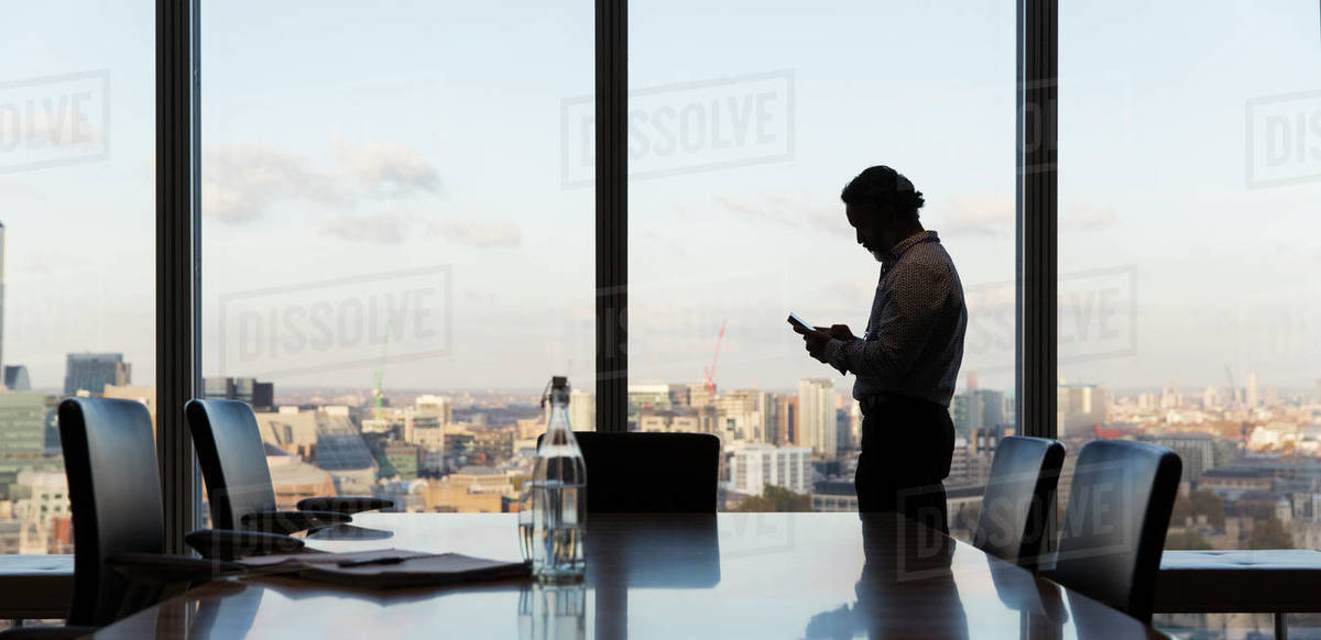 Businessman using smart phone at highrise office window, London, UK ...