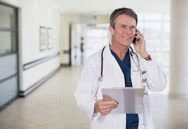 Doctor talking on cell phone in hospital corridor - Royalty-free Stock ...