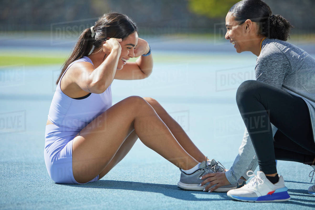 Happy female track and field athletes doing sit ups on track - Royalty ...