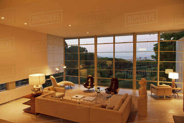 Modern living room overlooking trees and city in distance - Stock Photo ...