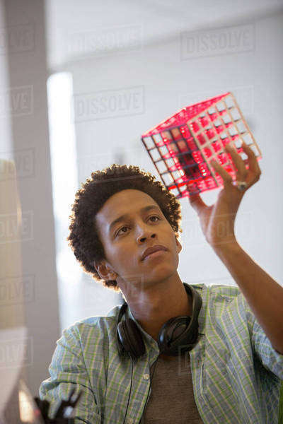 Businessman examining cube in office - Stock Photo - Dissolve