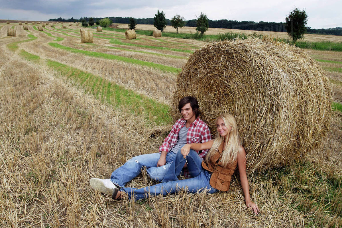Young couple leaning against haystack - Royalty-free Stock Photo | Dissolve