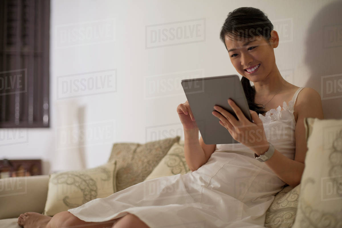 Woman sitting on sofa using digital tablet - Stock Photo - Dissolve