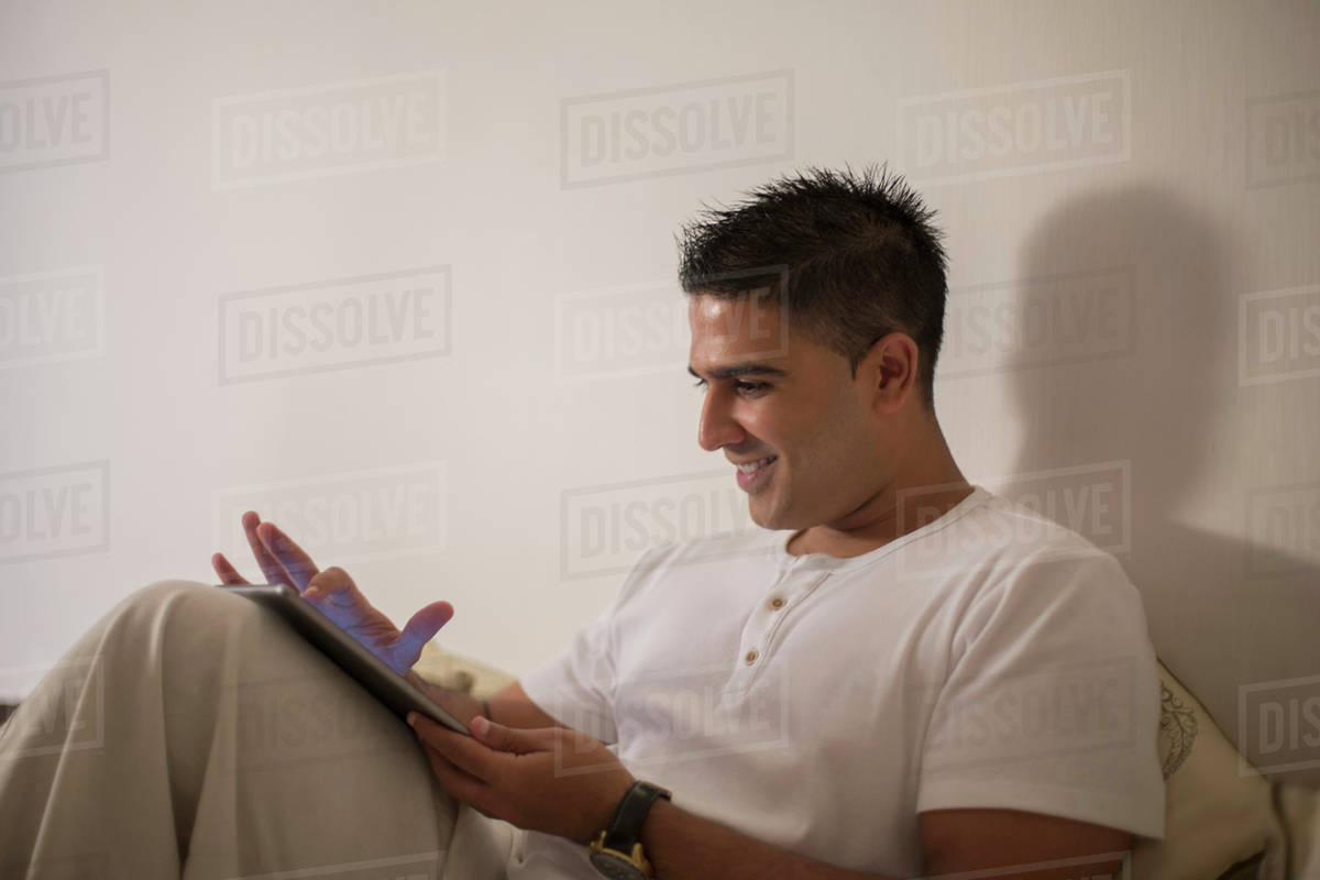 Young man sitting on sofa and using digital tablet - Royalty-free Stock ...