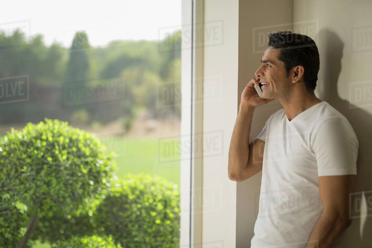 Man talking on mobile phone and looking through window - Royalty-free ...