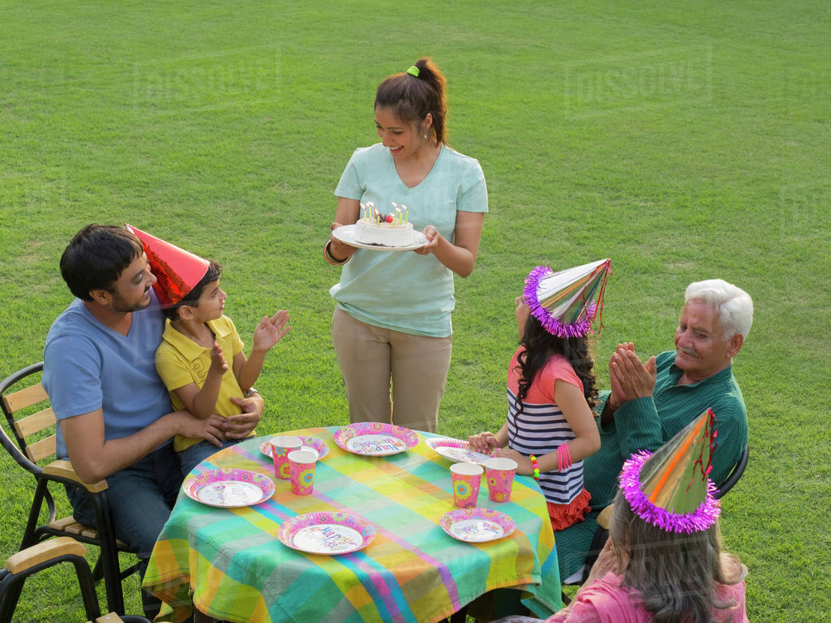 Mother bringing birthday cake to table with children, outside - Royalty ...