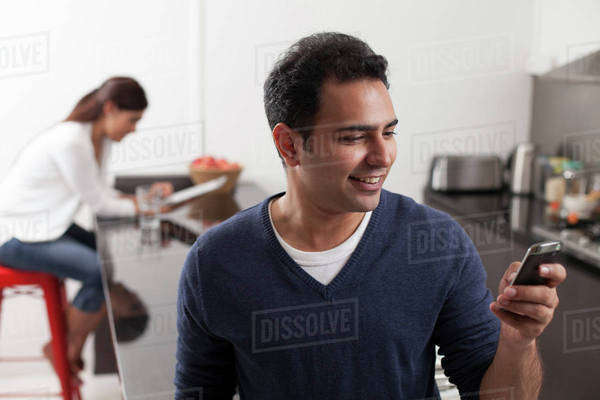 Young man texting in kitchen - Royalty-free Stock Photo | Dissolve