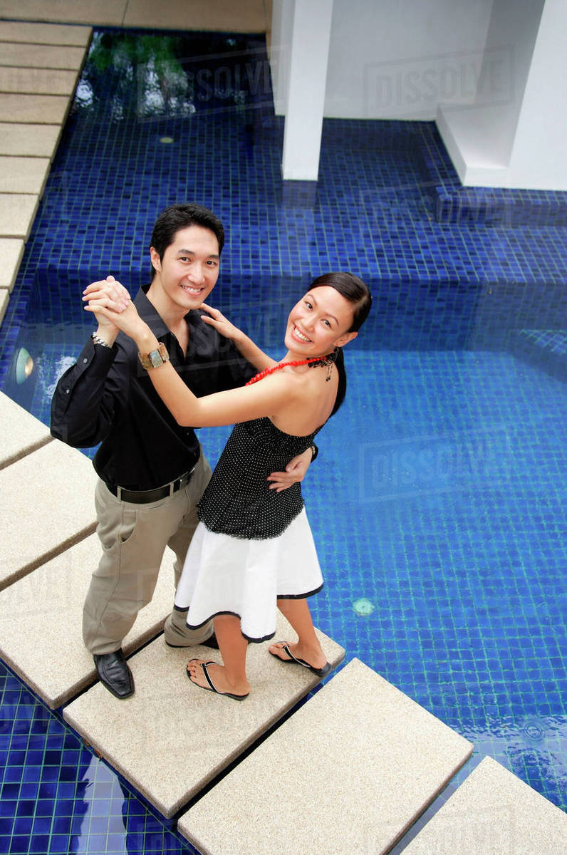 Couple dancing by swimming pool, smiling at camera - Royalty-free Stock ...