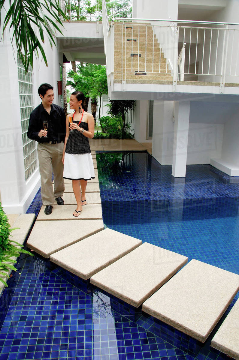 Couple walking by swimming pool - Royalty-free Stock Photo | Dissolve