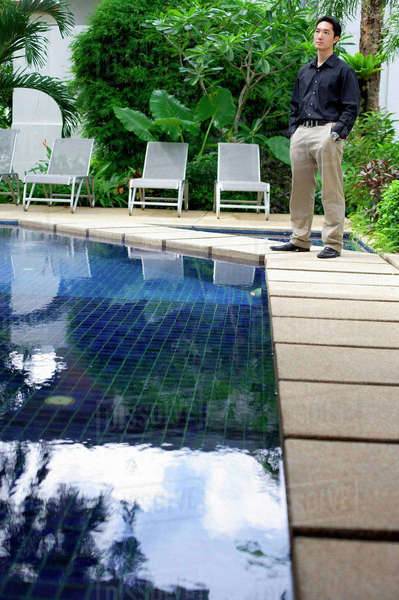 Man standing by swimming pool, hands in pocket - Royalty-free Stock ...