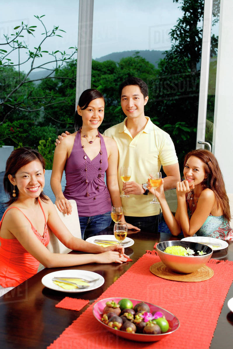 Young adults around dinner table, smiling at camera - Royalty-free ...