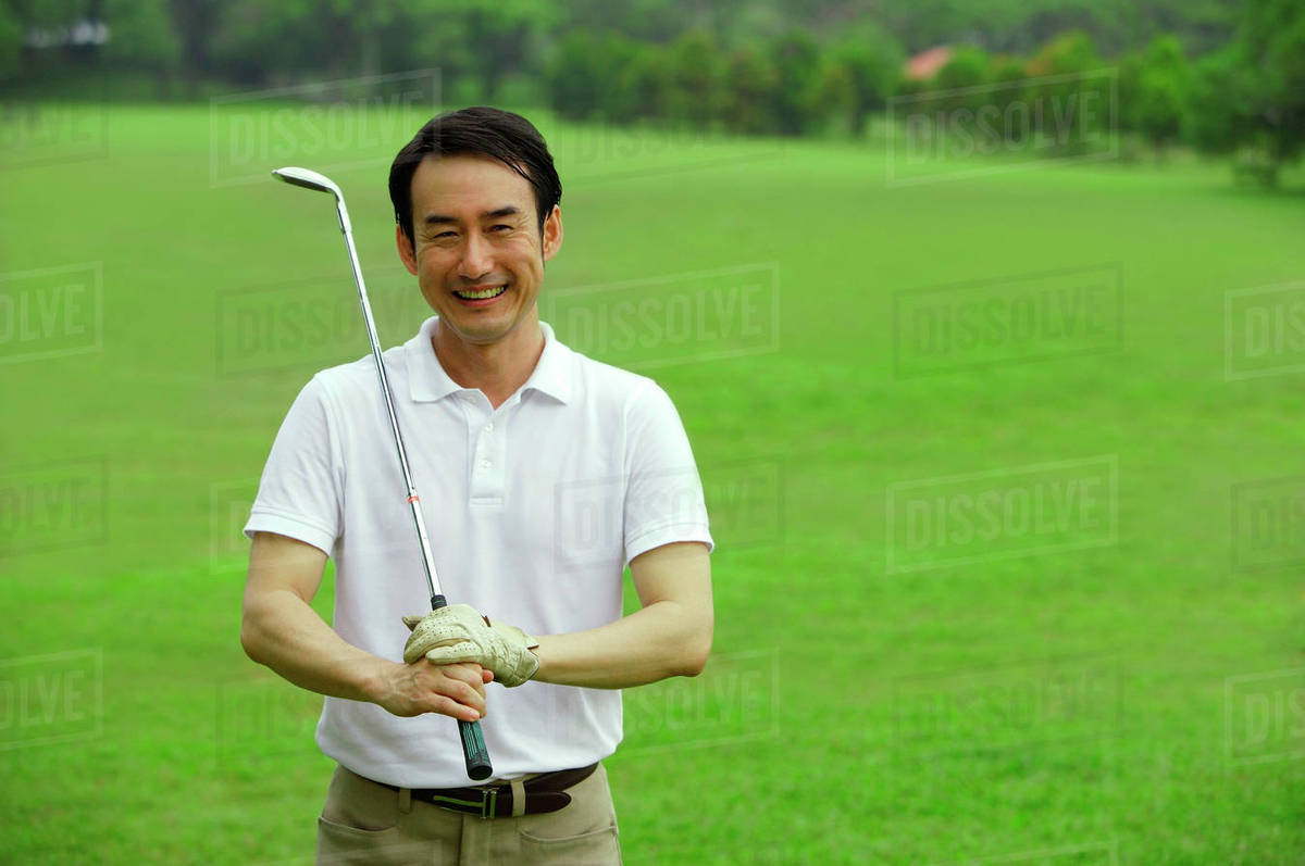 Man holding golf club, smiling at camera - Royalty-free Stock Photo ...