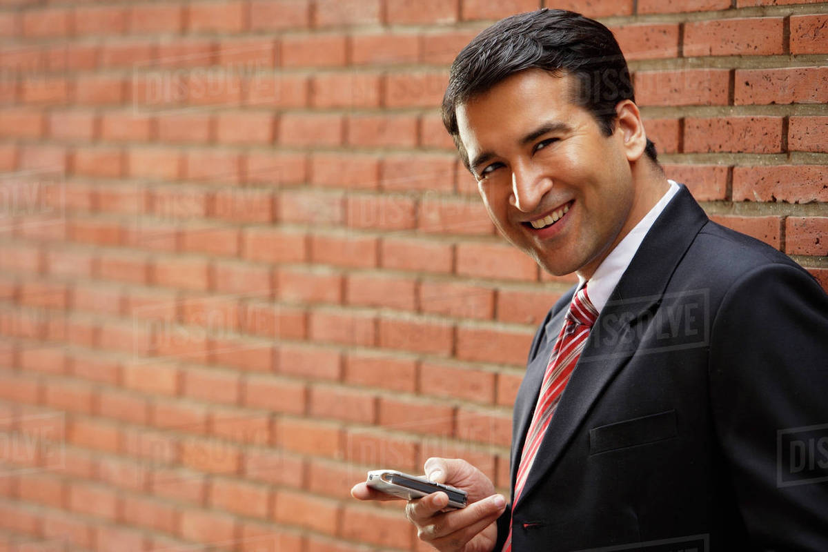 Businessman leaning against wall - Royalty-free Stock Photo | Dissolve