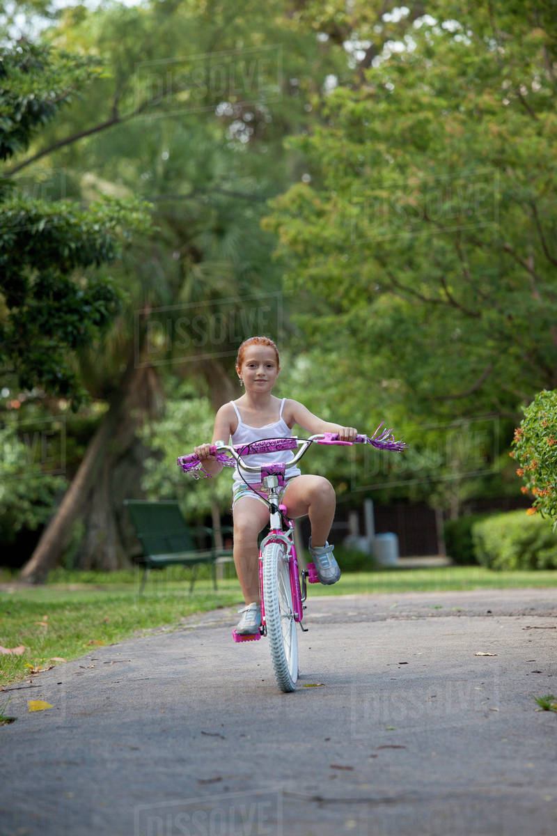 Girl riding bike through park - Royalty-free Stock Photo | Dissolve