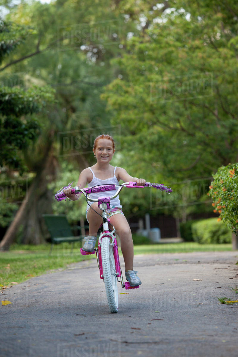 Girl riding bike through park - Royalty-free Stock Photo | Dissolve